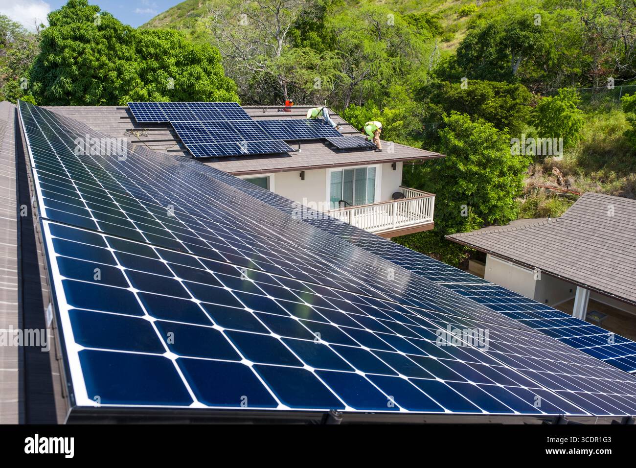 Men wearing safety harnesses installing photovoltaic panels during a ...