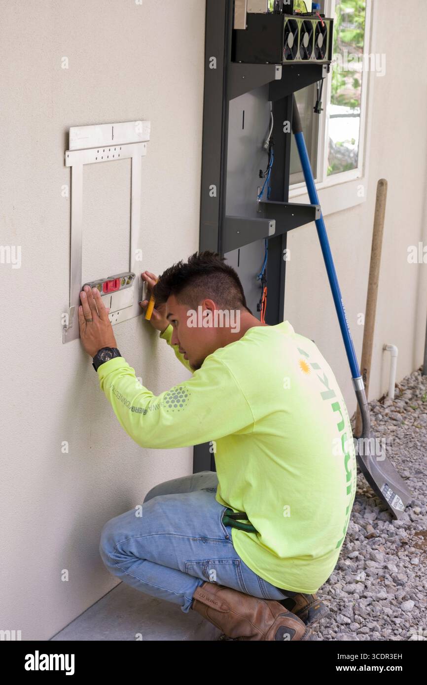 Young man using a spirt level during installation of wall mount for ...