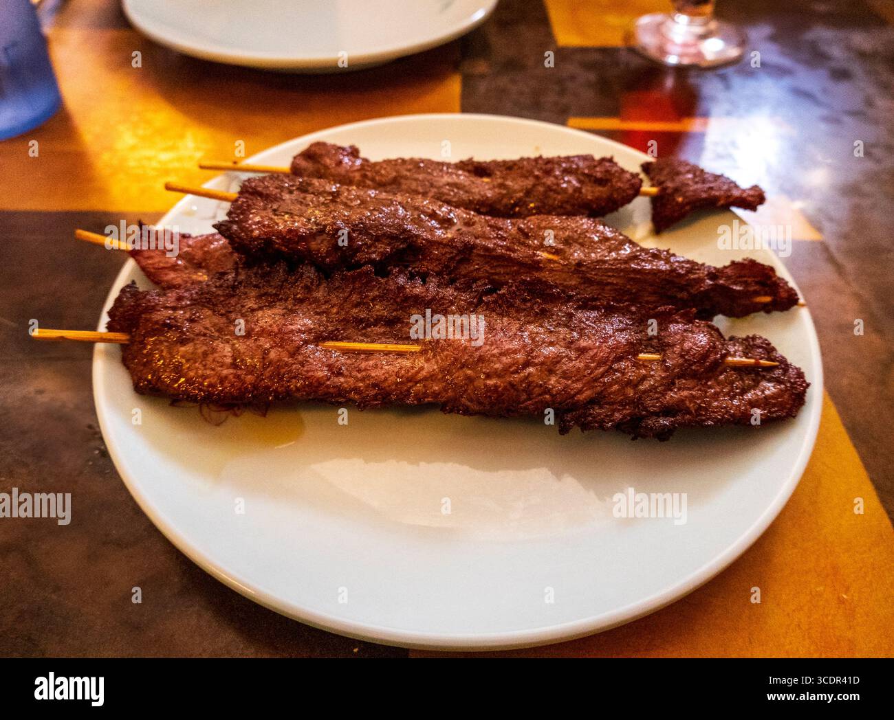 Juicy grilled beef skewers served on a white plate, showcasing a rich ...