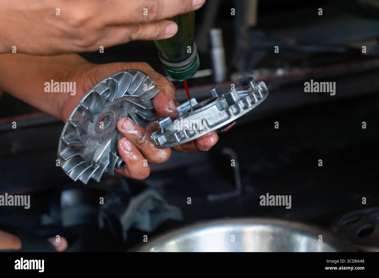 Mechanic’s hand performing maintenance on a scooter motorcycle’s CVT ...
