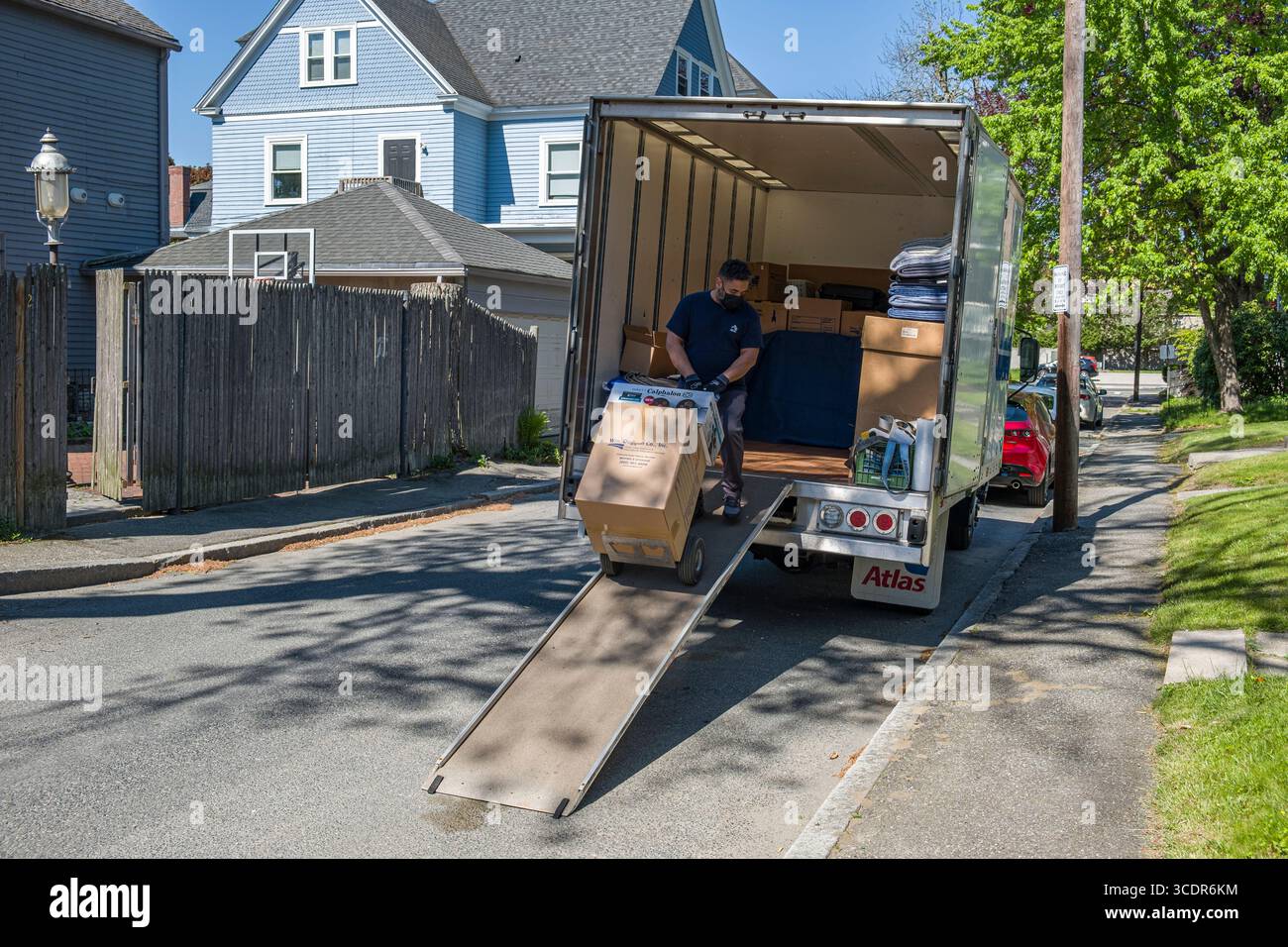 Mover pulling hand truck loaded with boxes up ramp into the back of a ...