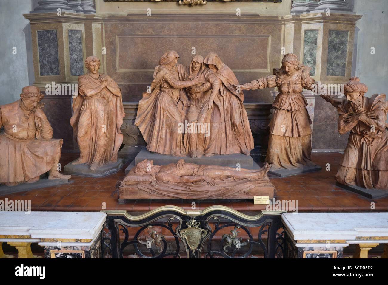 A terracotta sculpture of a weeping Virgin Mary next to votive candles ...