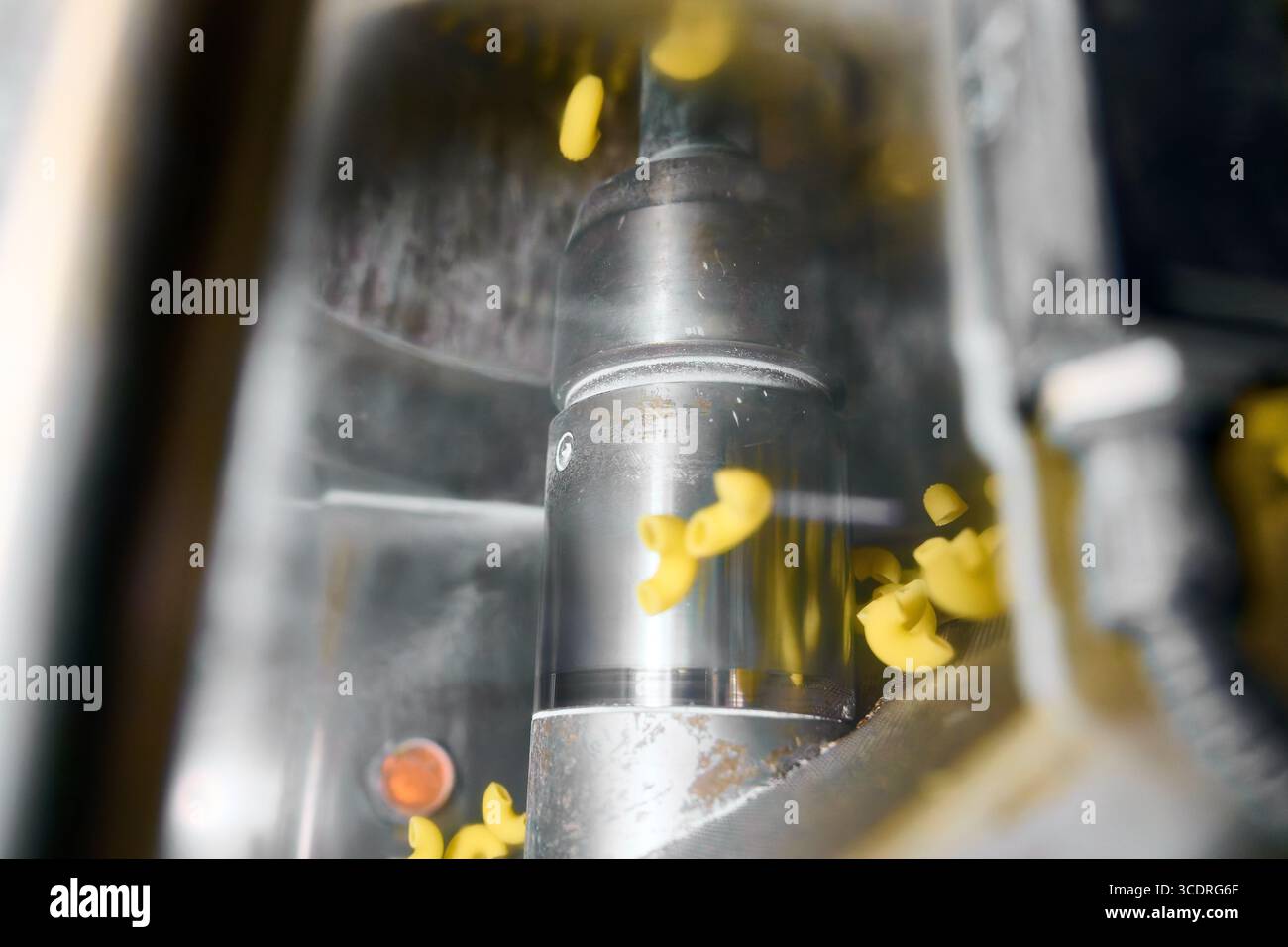 Pasta extrusion process in a modern kitchen during daylight hours with ...
