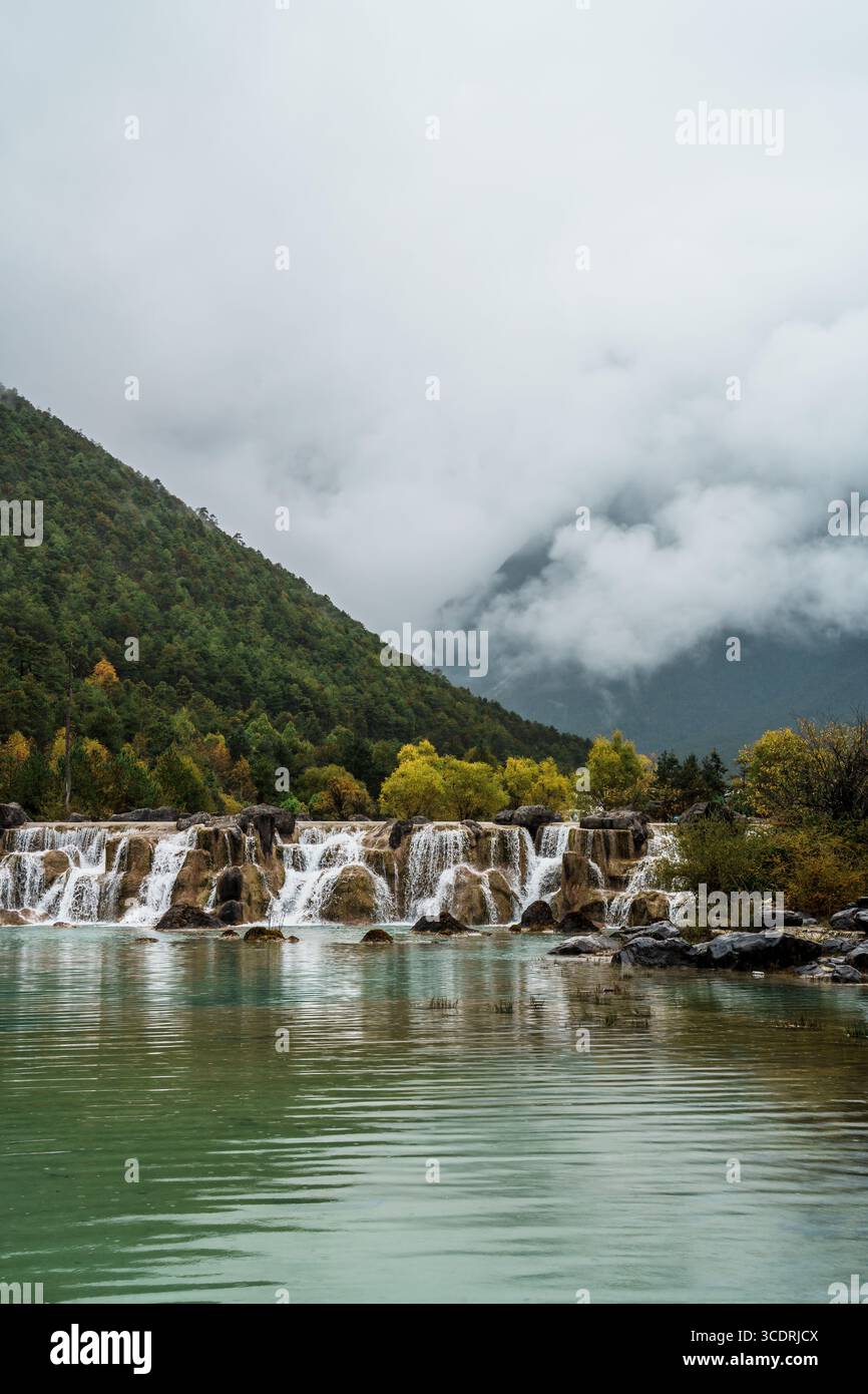 Majestic multi-tiered waterfall flows into turquoise water against a ...