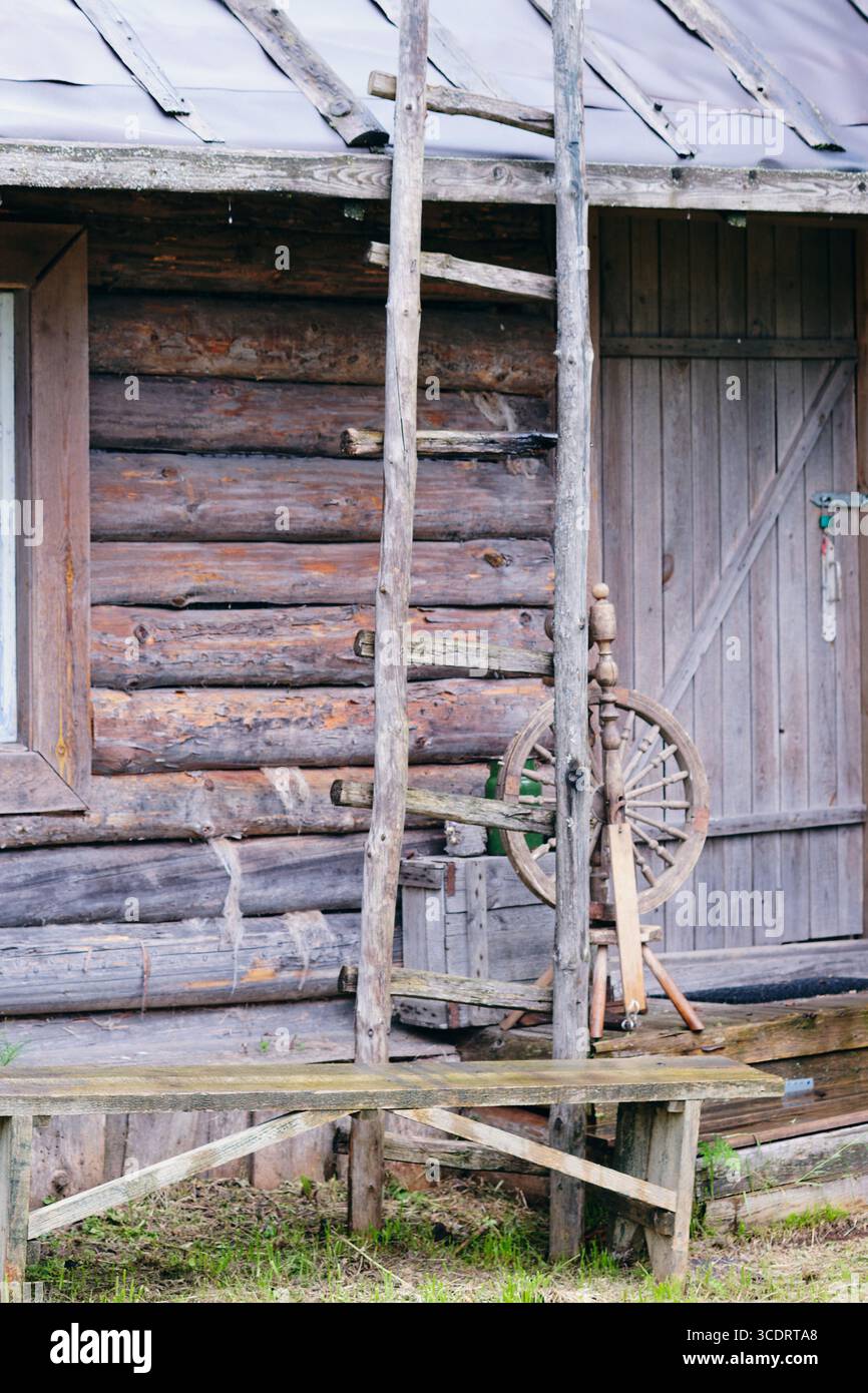 A wooden cabin stands with an attached ladder and a spinning wheel, set ...