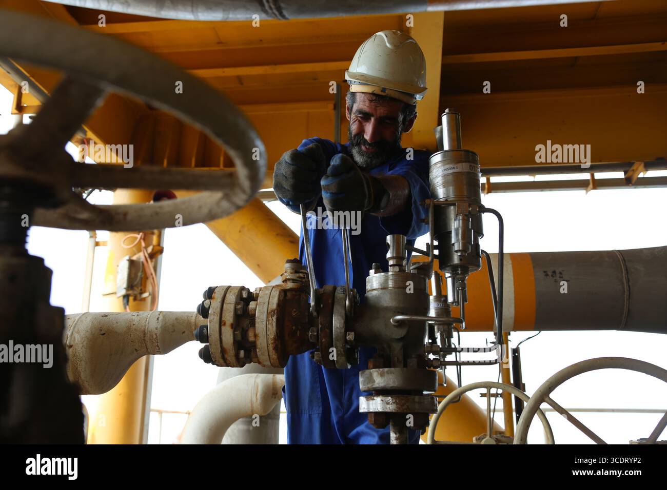 Offshore oil worker operating a valve on a gas platform in the Persian ...