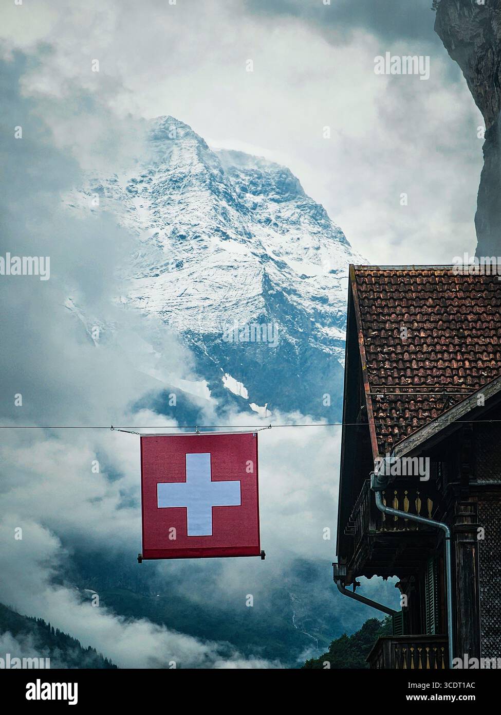 Traditional Swiss Chalet With National Flag and Snowy Alpine Peak in ...