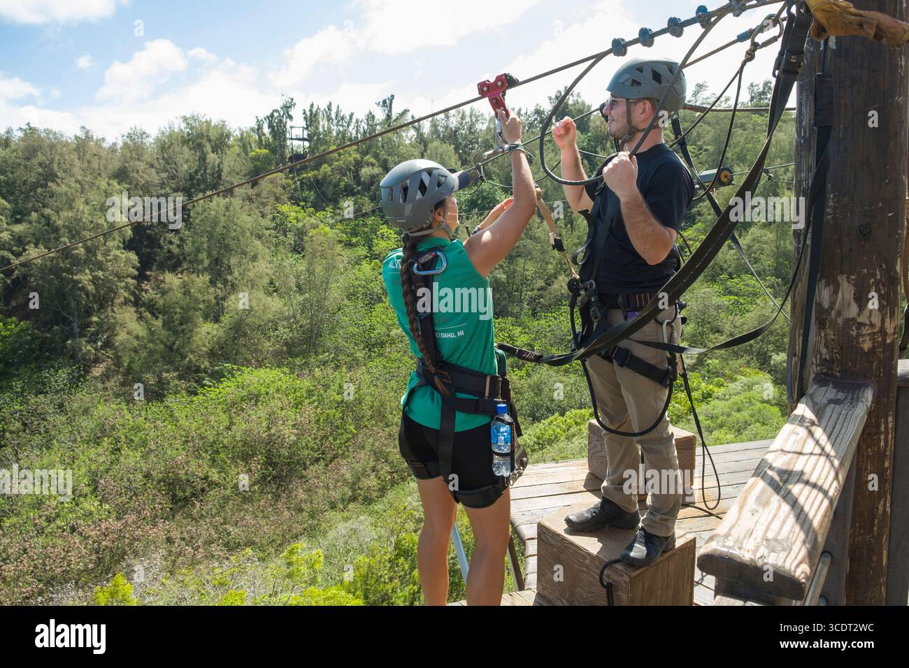 Guide checking safety equipment of male client during a zip-line tour ...