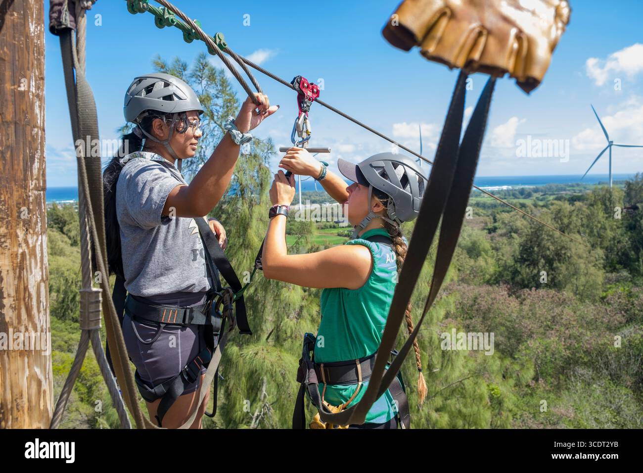 Guide checking safety equipment of female client during a zip-line tour ...