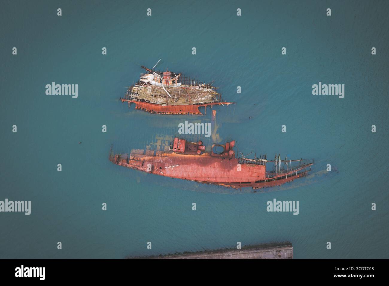 Aerial view of rust-colored shipwrecks against the teal waters of the ...