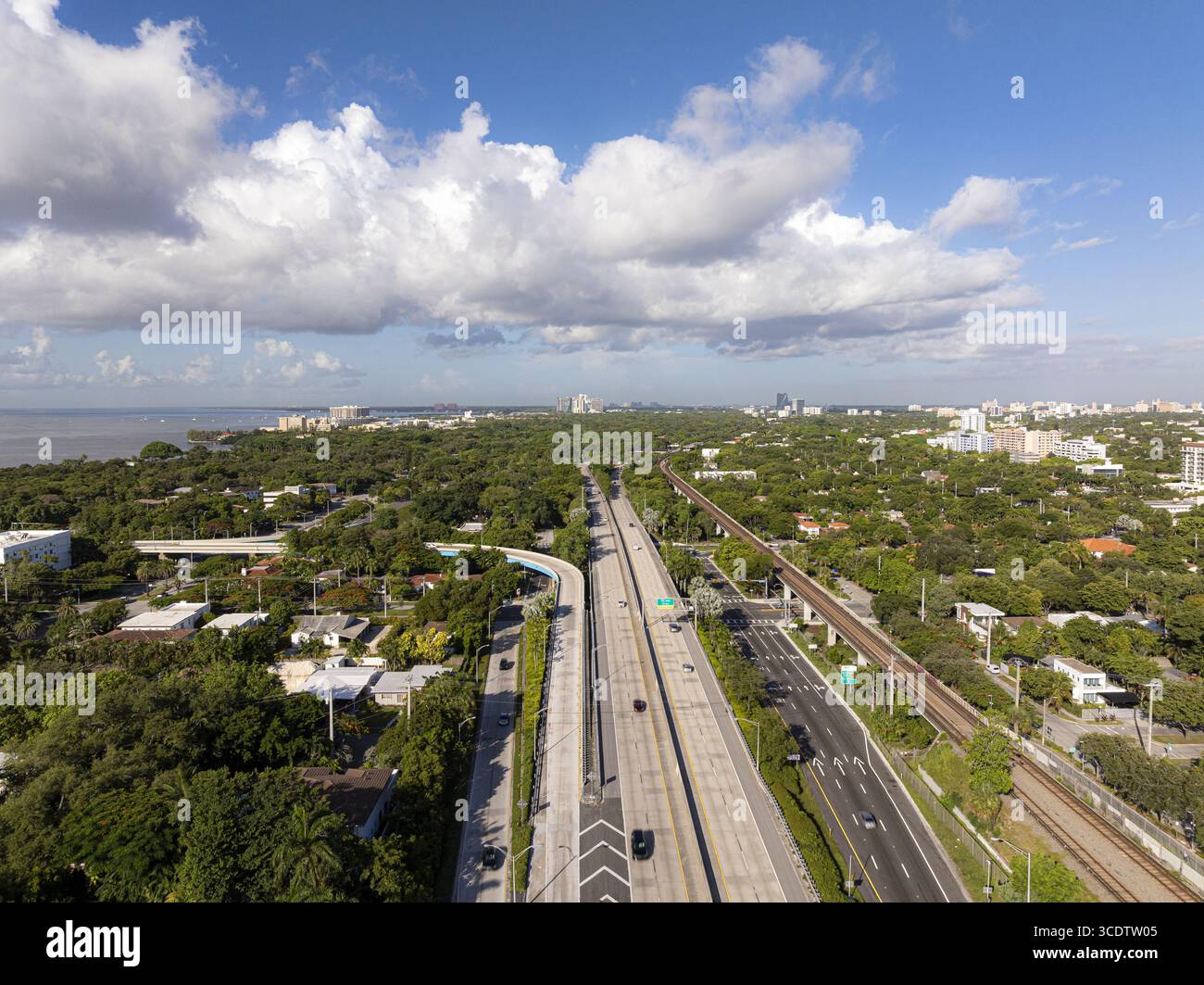 Aerial view of a highway cutting through lush greenery, with a monorail ...