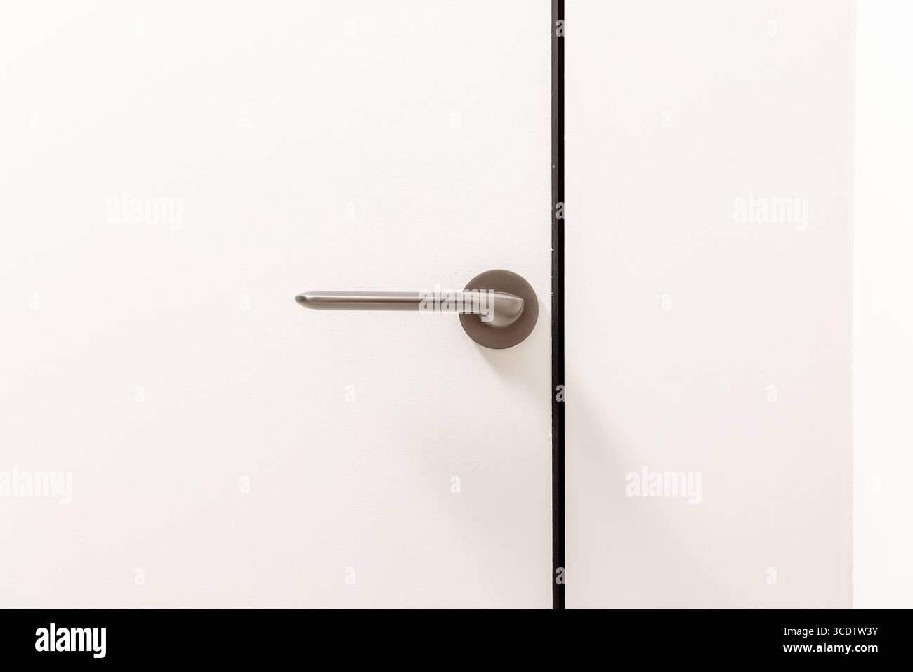 A silver door handle is shown in a mirror. The handle is turned to the ...