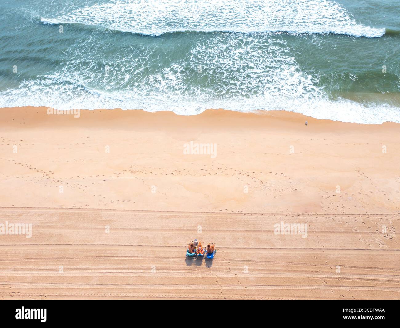 Aerial view of the meeting point of the sandy beach and the foamy waves ...