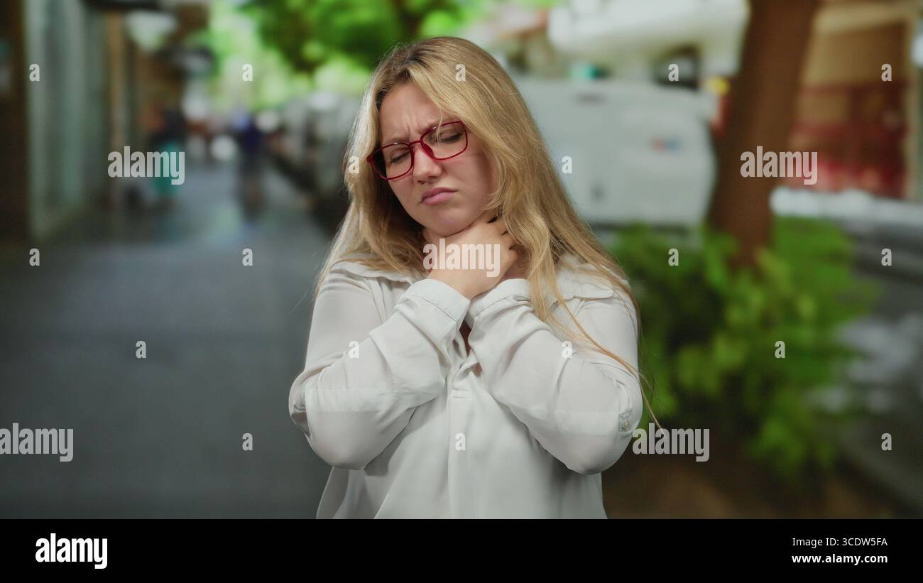 Woman choking while standing outdoors on a city street, surrounded by ...