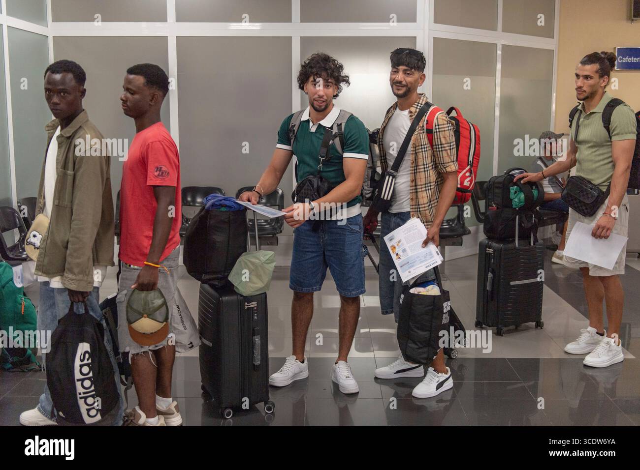 A group of people queue at the Port of Ceuta, before being transferred ...
