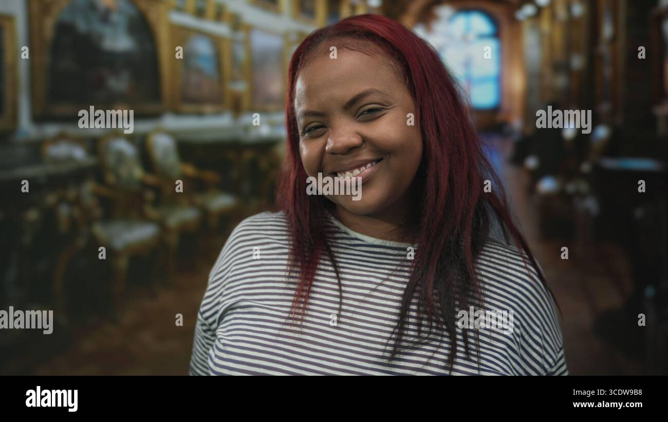 Woman smiles in a museum hall with framed paintings on the walls and a ...