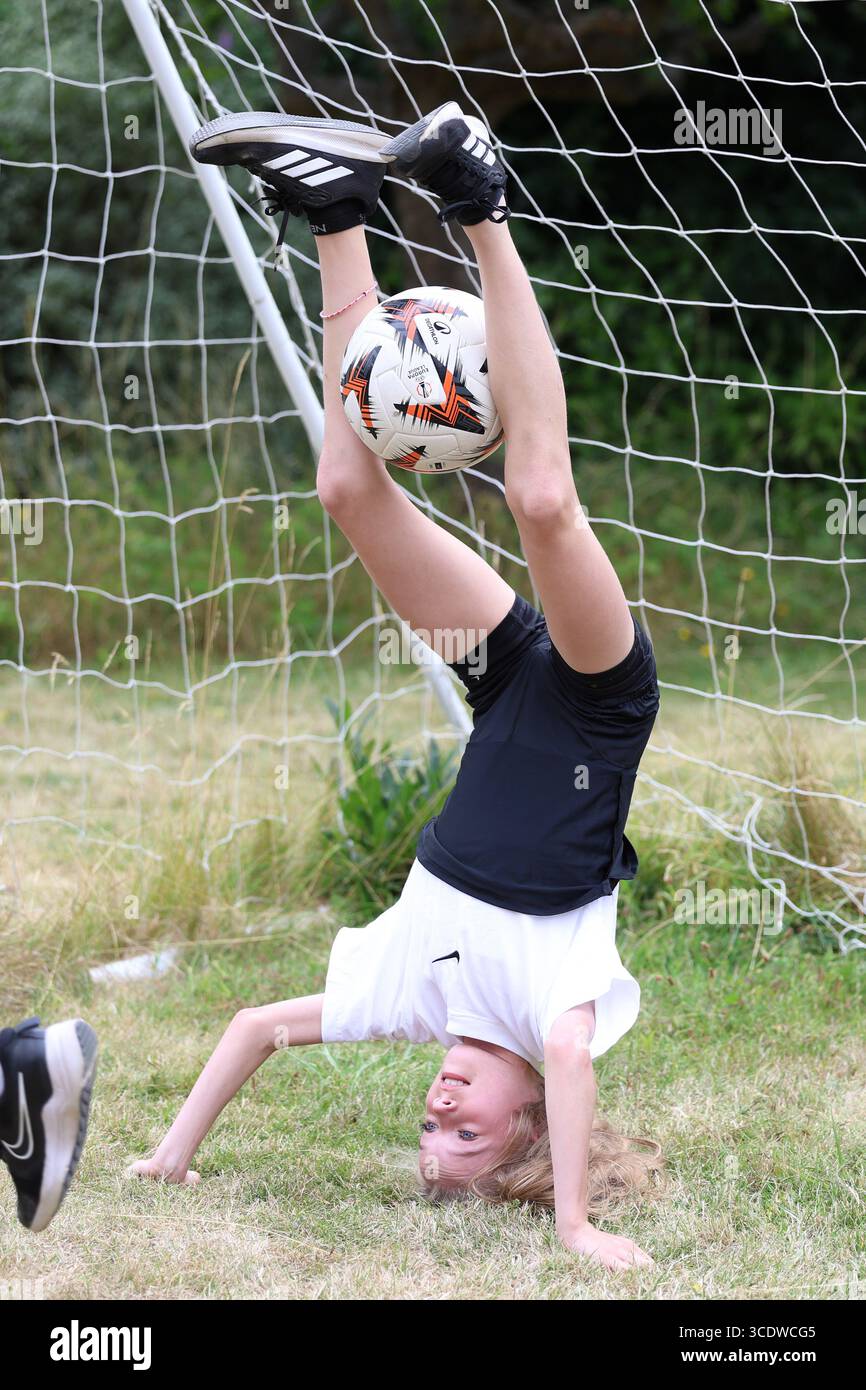 Girl doing headstand holds football between legs balancing Stock Photo ...