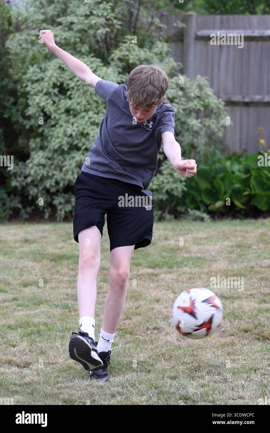 Boy playing football shooting and volleying ball Stock Photo - Alamy
