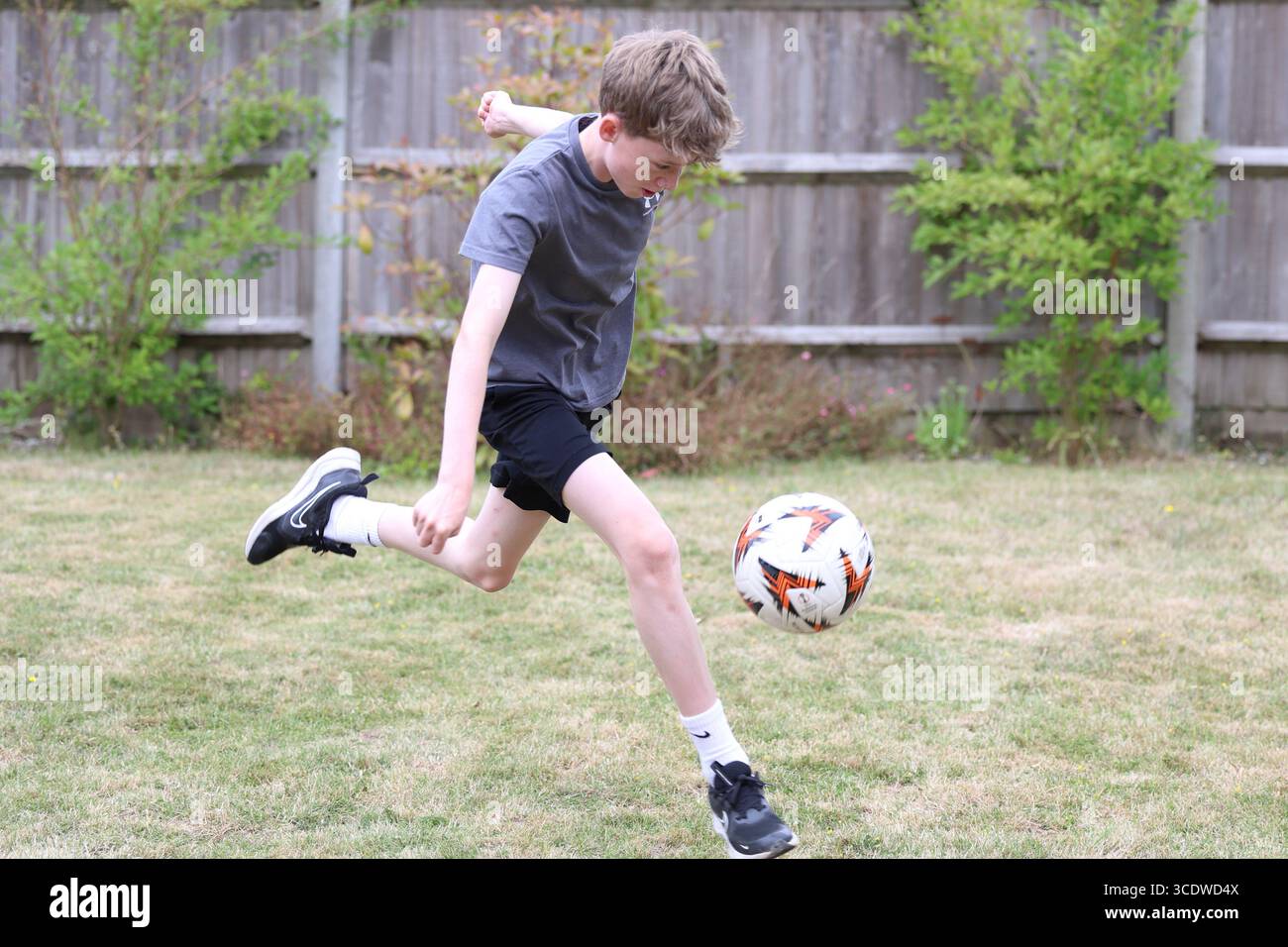 Boy playing football shooting and volleying ball Stock Photo - Alamy
