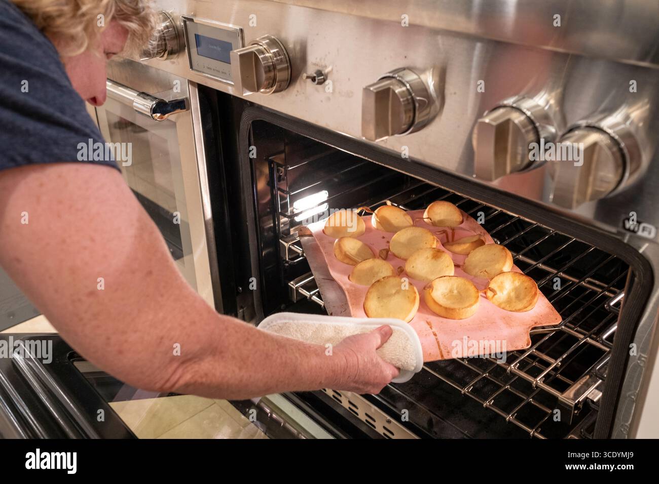 Woman removing traditional Yorkshire Pudding from oven, USA Stock Photo ...