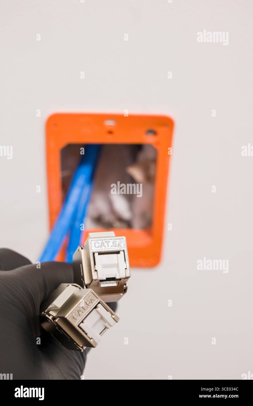 Gloved hand holding CAT6A Ethernet cable terminated in 180 keystone ...