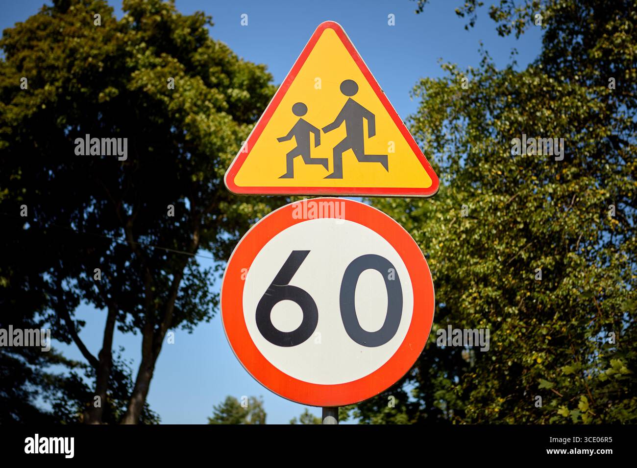 A triangular warning sign for children crossing above a circular 60 kmh ...
