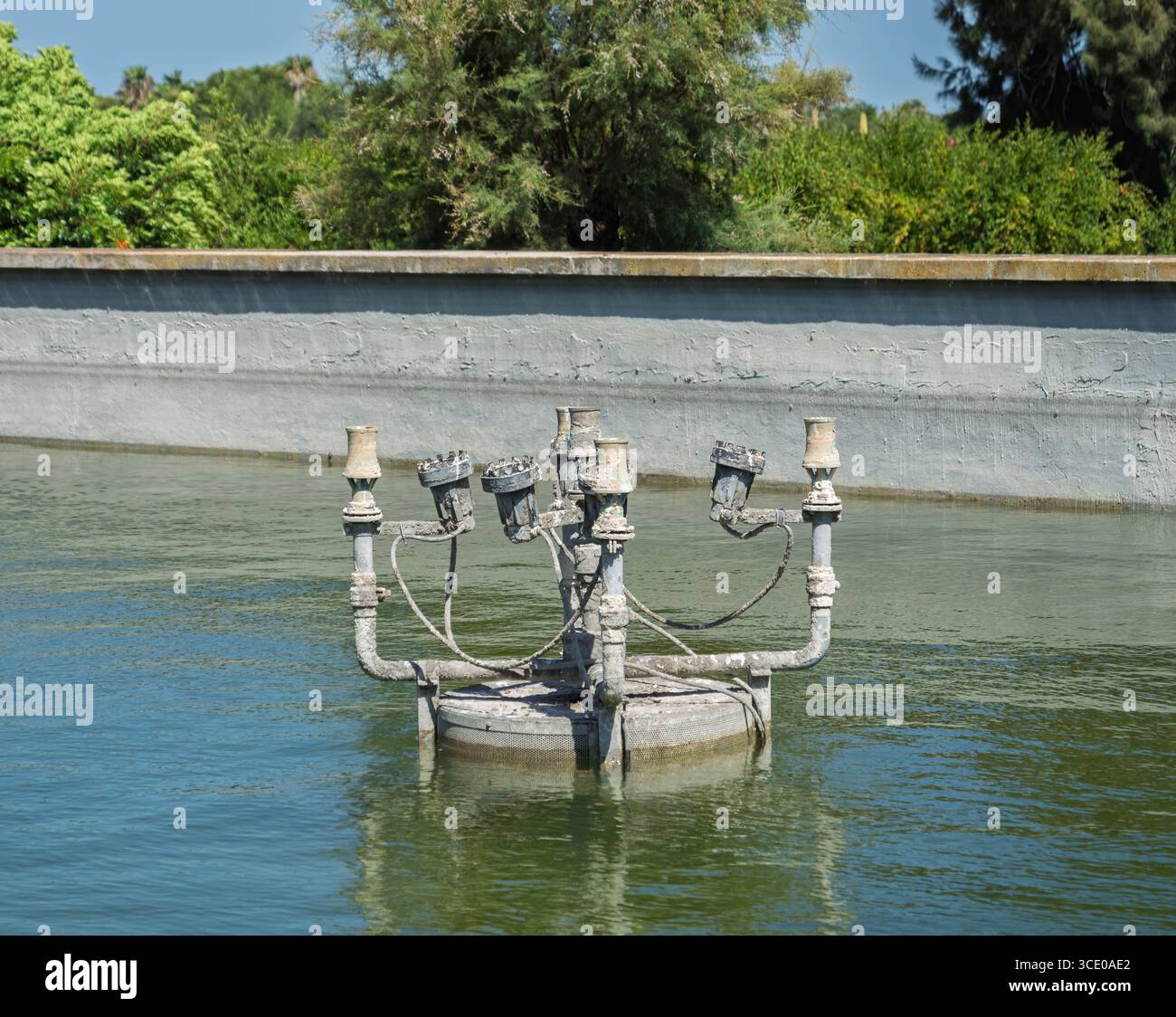 Industrial-looking weathered pipe fixture rising from a greenish water ...