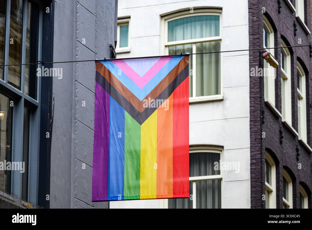 A colorful pride flag hanging between buildings, featuring a chevron ...
