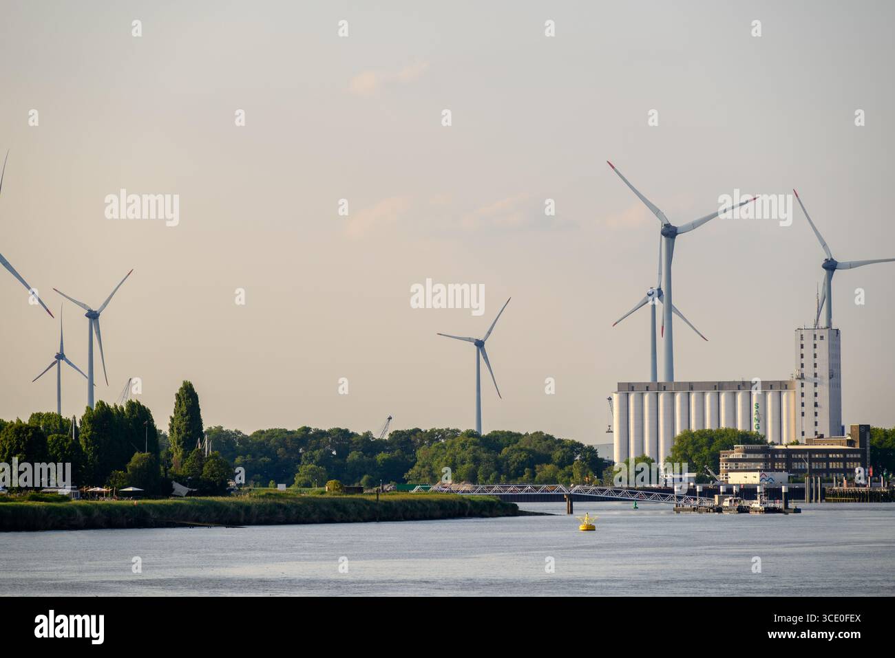 Wind turbines along a waterfront of Scheldt River within industrial ...