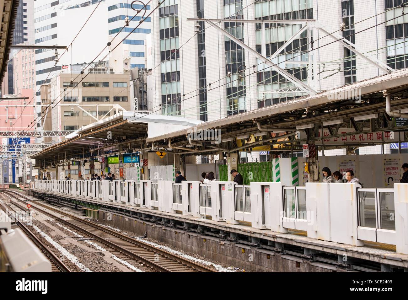 People standing on train platform behind platform edge doors, Tamachi ...