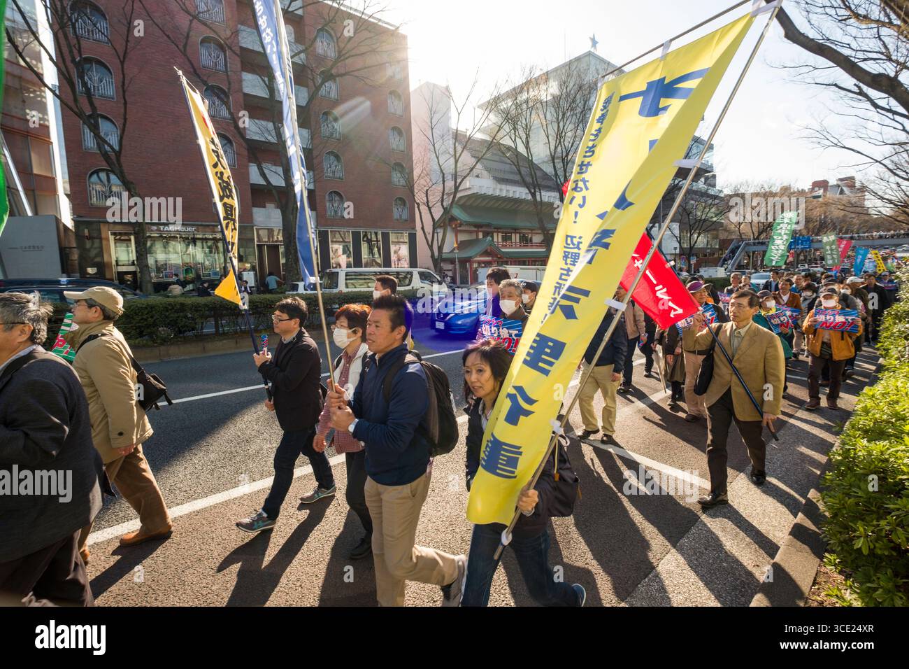 Crowd of people marching on Omotesando dori holding banners and signs ...