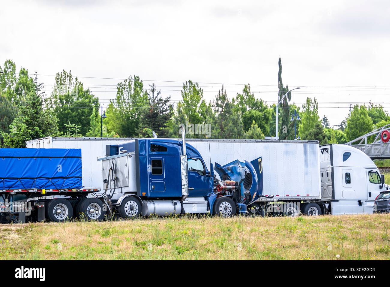 Broken blue big rig semi truck tractor with open hood and loaded flat ...