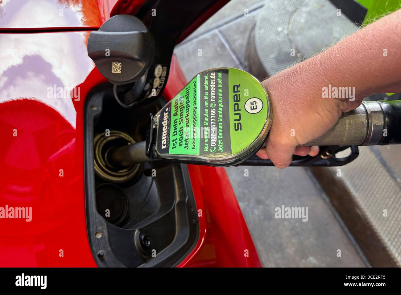 Ein Auto wird mit SUPER E5 betankt. Tankpistole im Tank, Tankstutzen ...