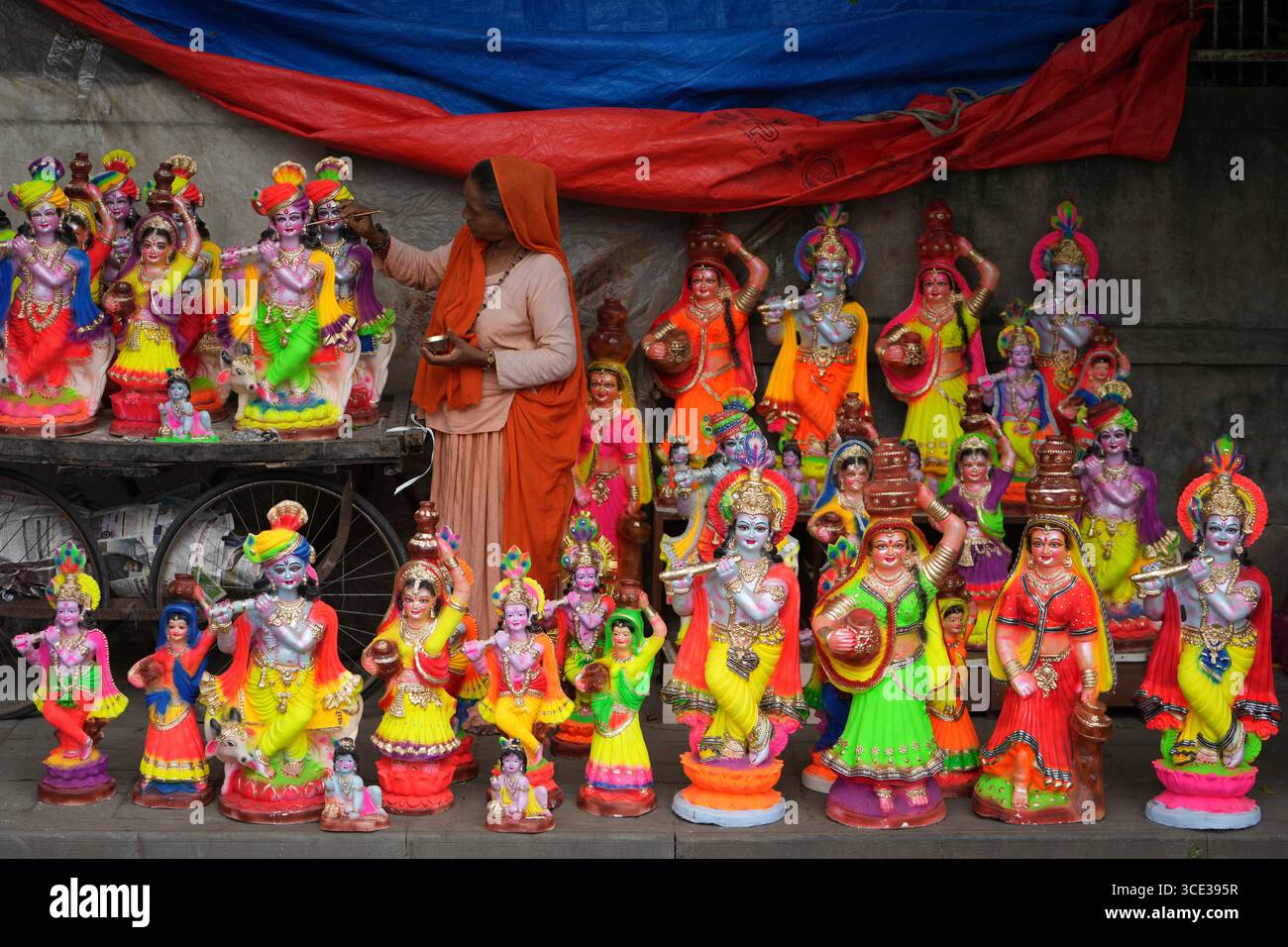 A woman selling idols of Hindu god Krishna and his consort Radha, gives ...