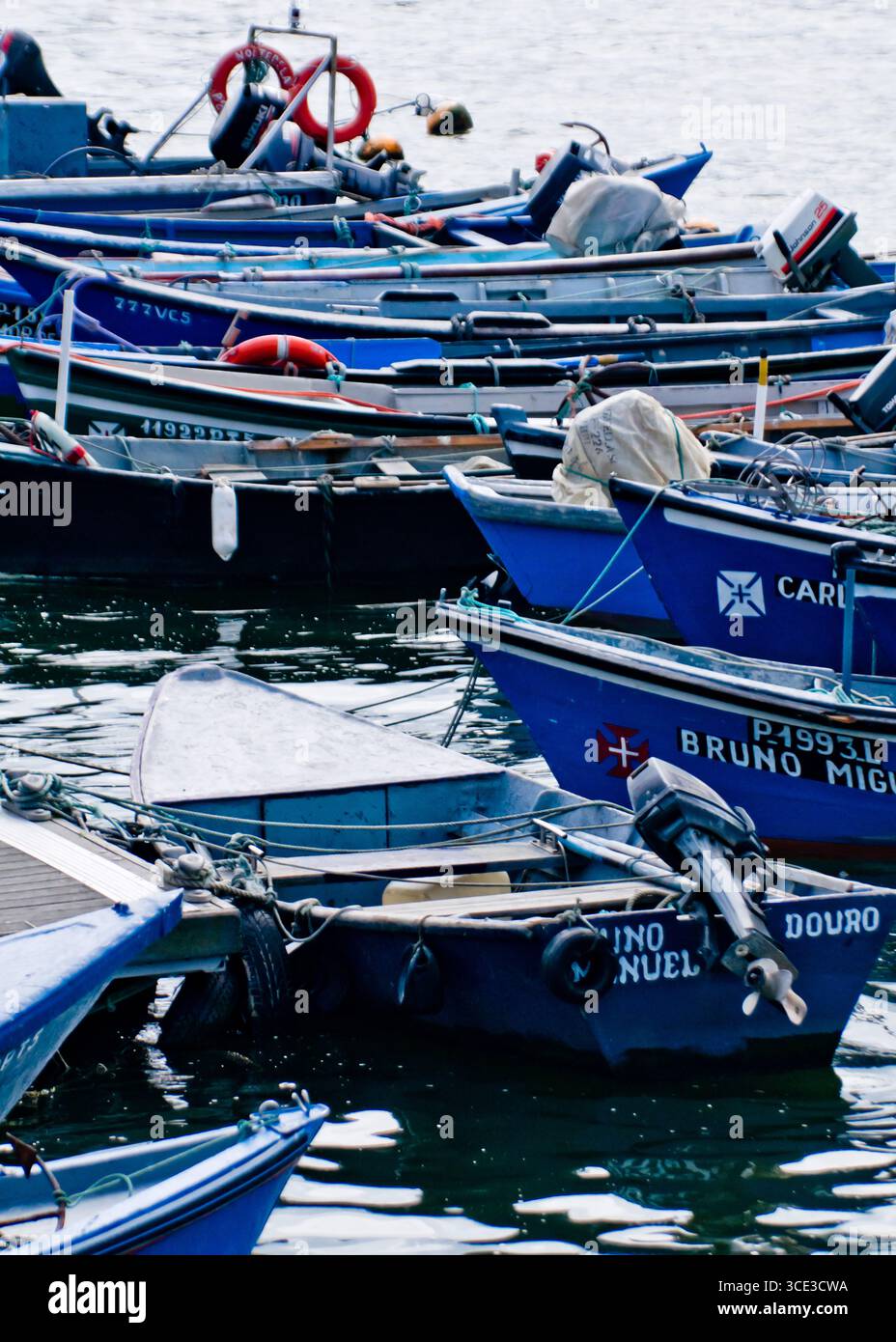 A collection of small fishing boats are docked in the water. The boats ...