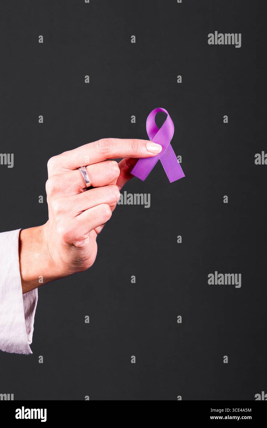 Woman’s hand holding a periwinkle ribbon, symbol of esophageal cancer ...