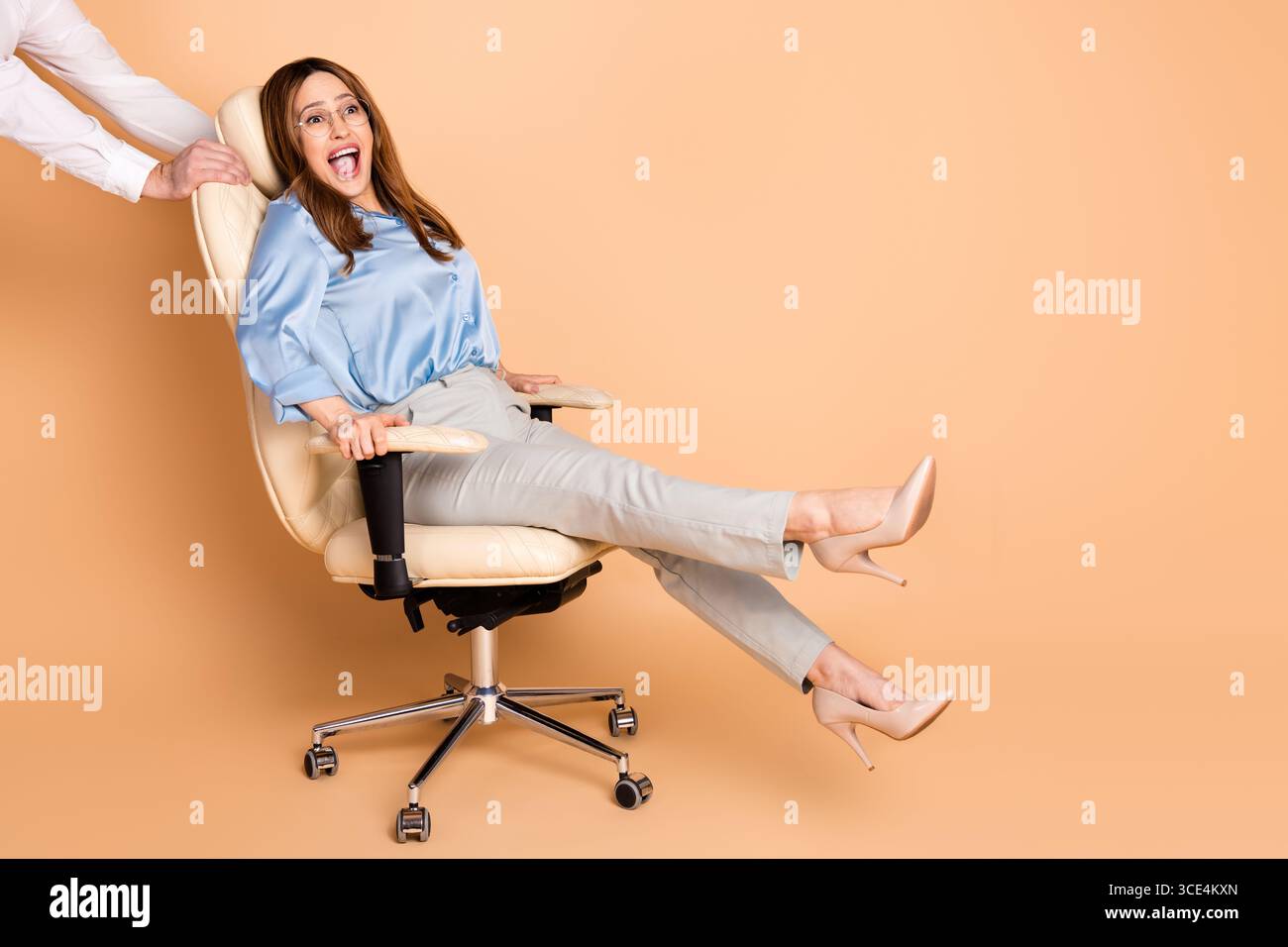 Cheerful businesswoman leaning back in an office chair being playfully ...