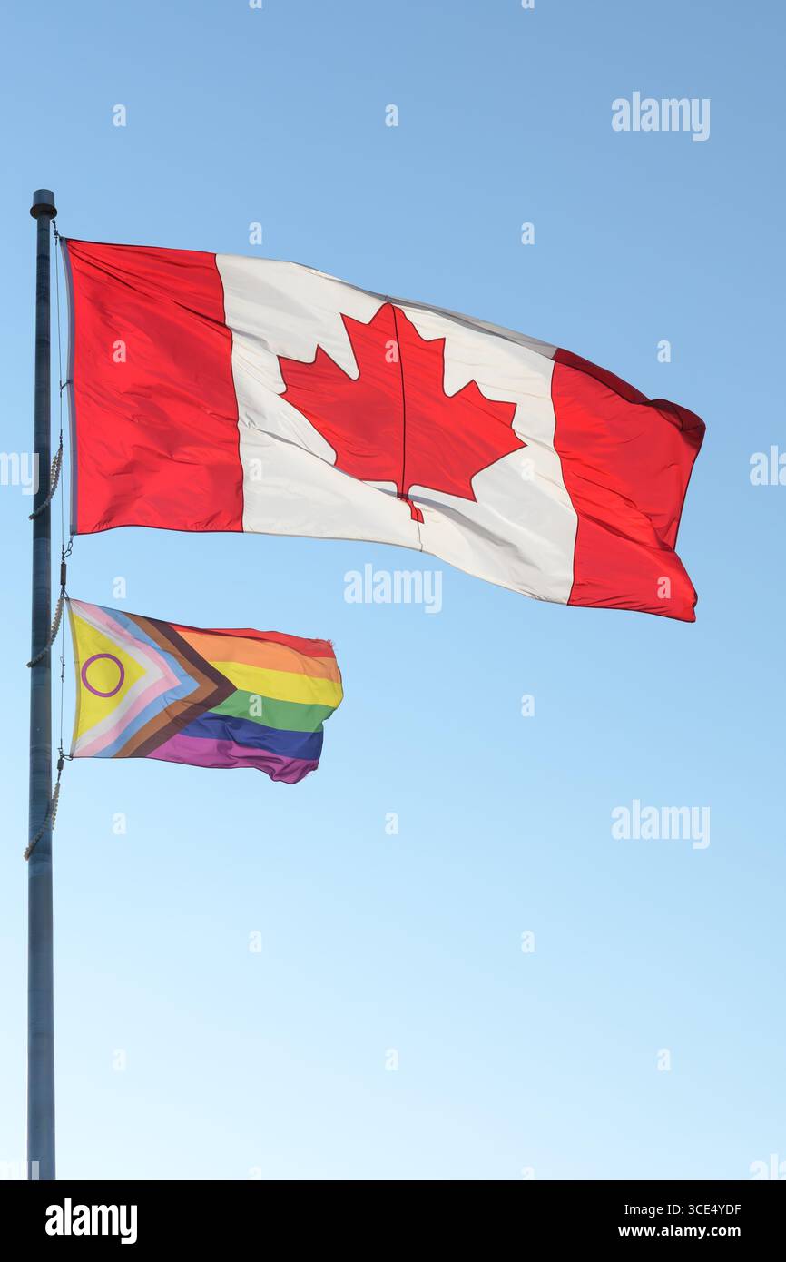 The Canadian flag and an inclusive pride flag wave on a tall pole ...