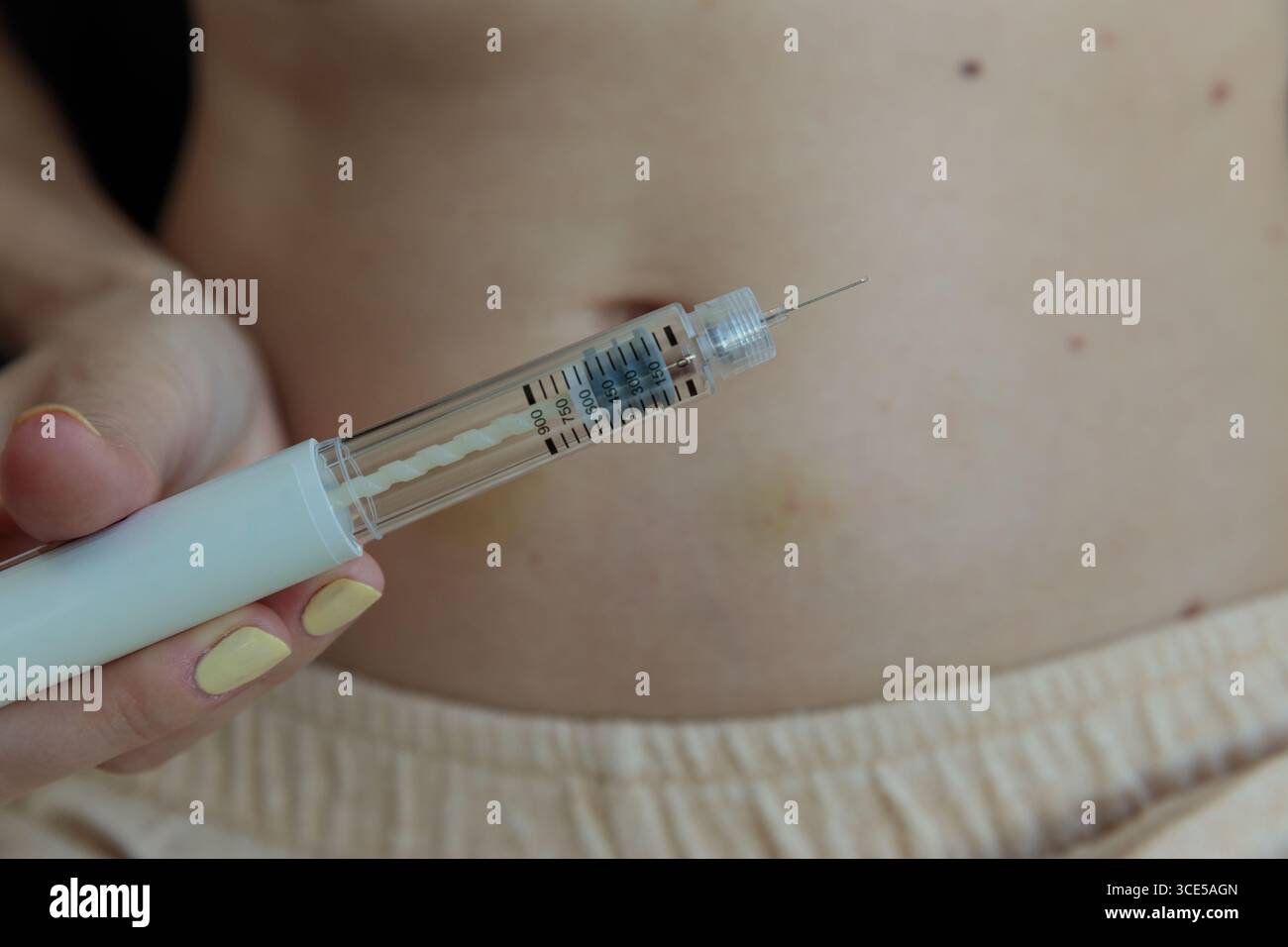 The image features a person's hand gripping a syringe, poised over ...