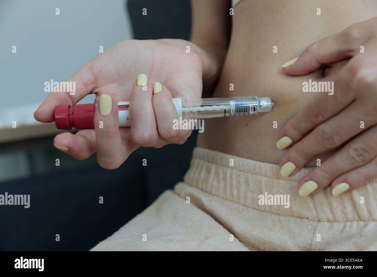 An image showing a person preparing to self-inject medication into the ...