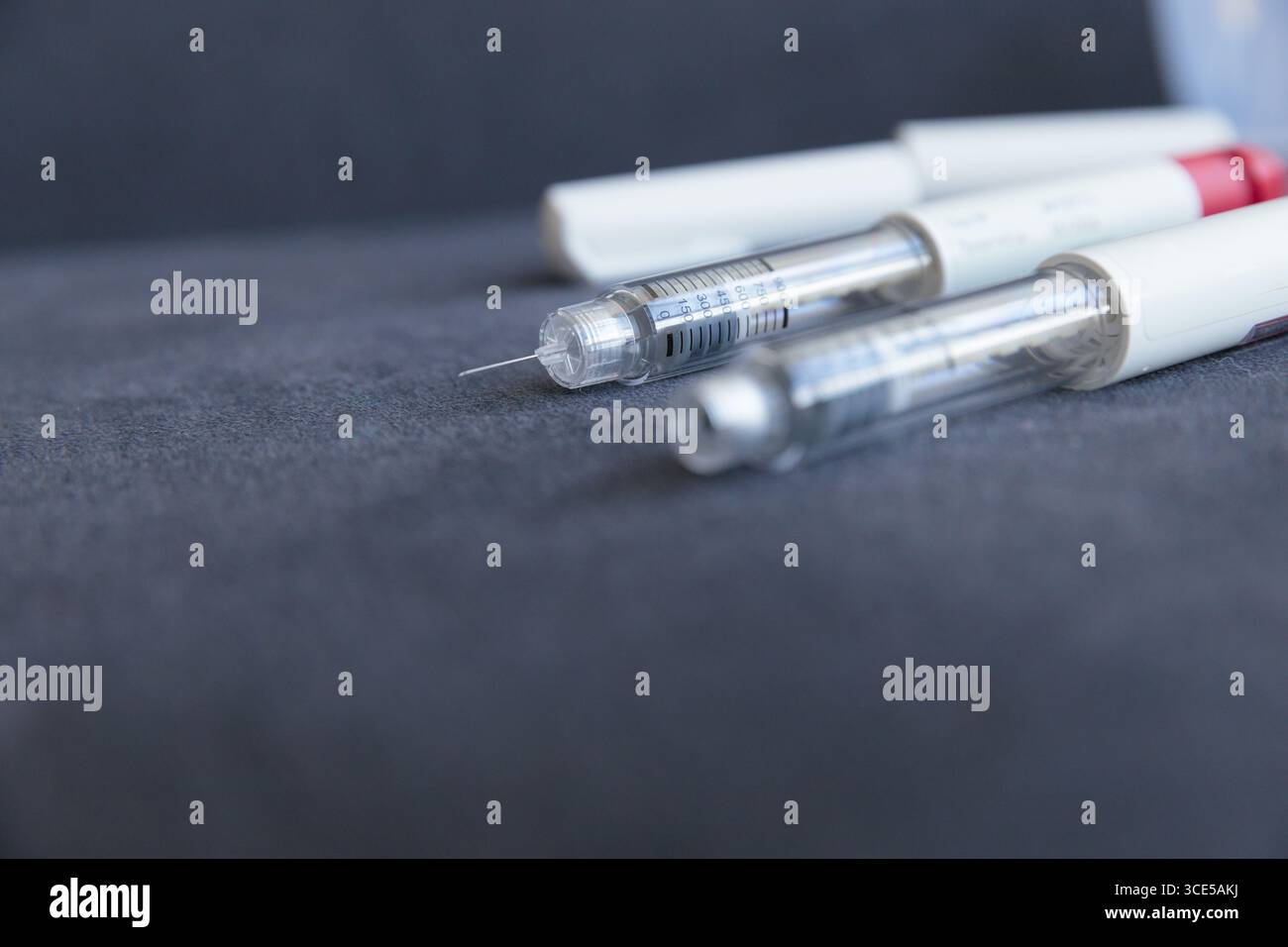 captures medical syringes resting on dark surface, showcasing their ...