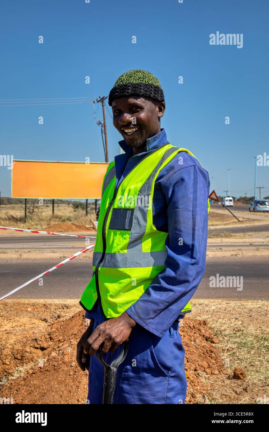 African road construction worker with a shovel digging a trench ditch ...