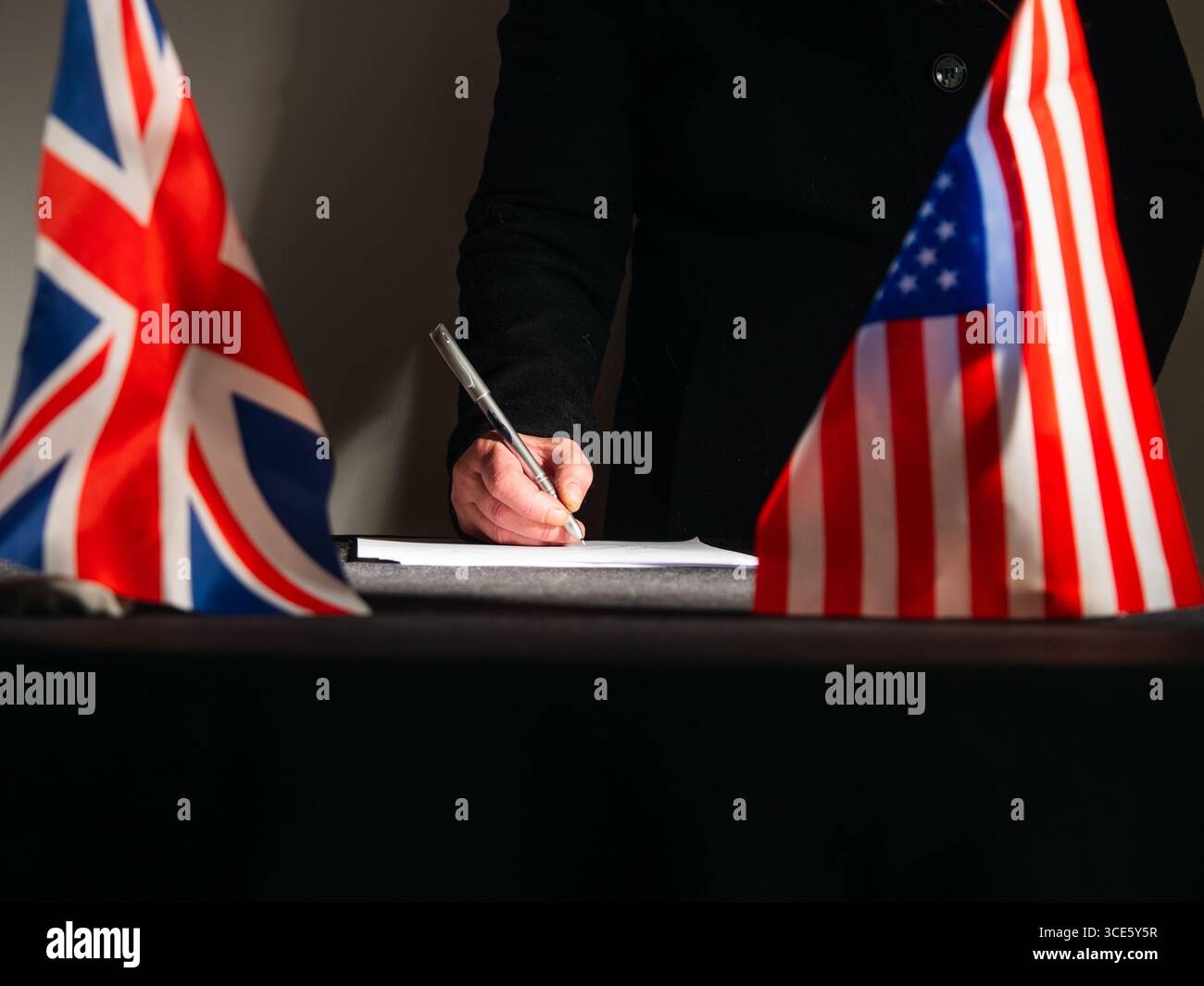 Hand signing a trade deal with American USA flag and British Union Jack ...