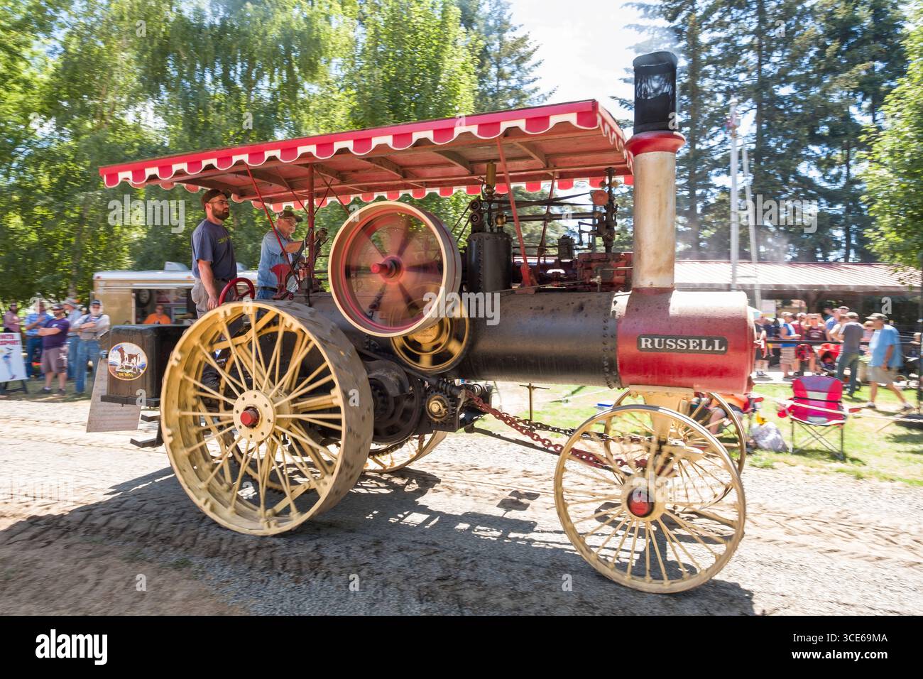 Man driving an Russell steam powered traction engine past spectators ...
