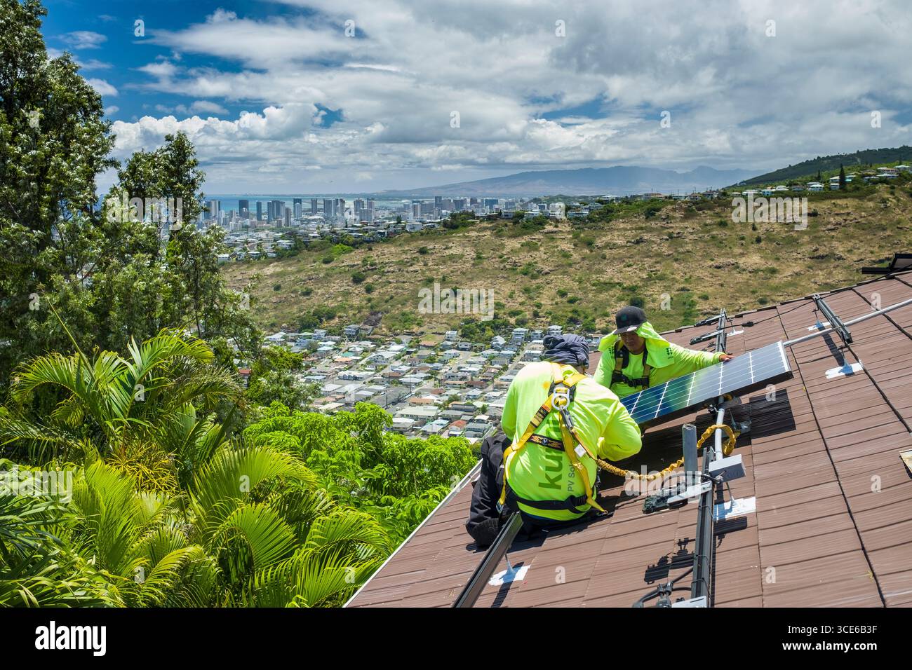 Men on rooftop installing photovoltaic panels onto support rails ...