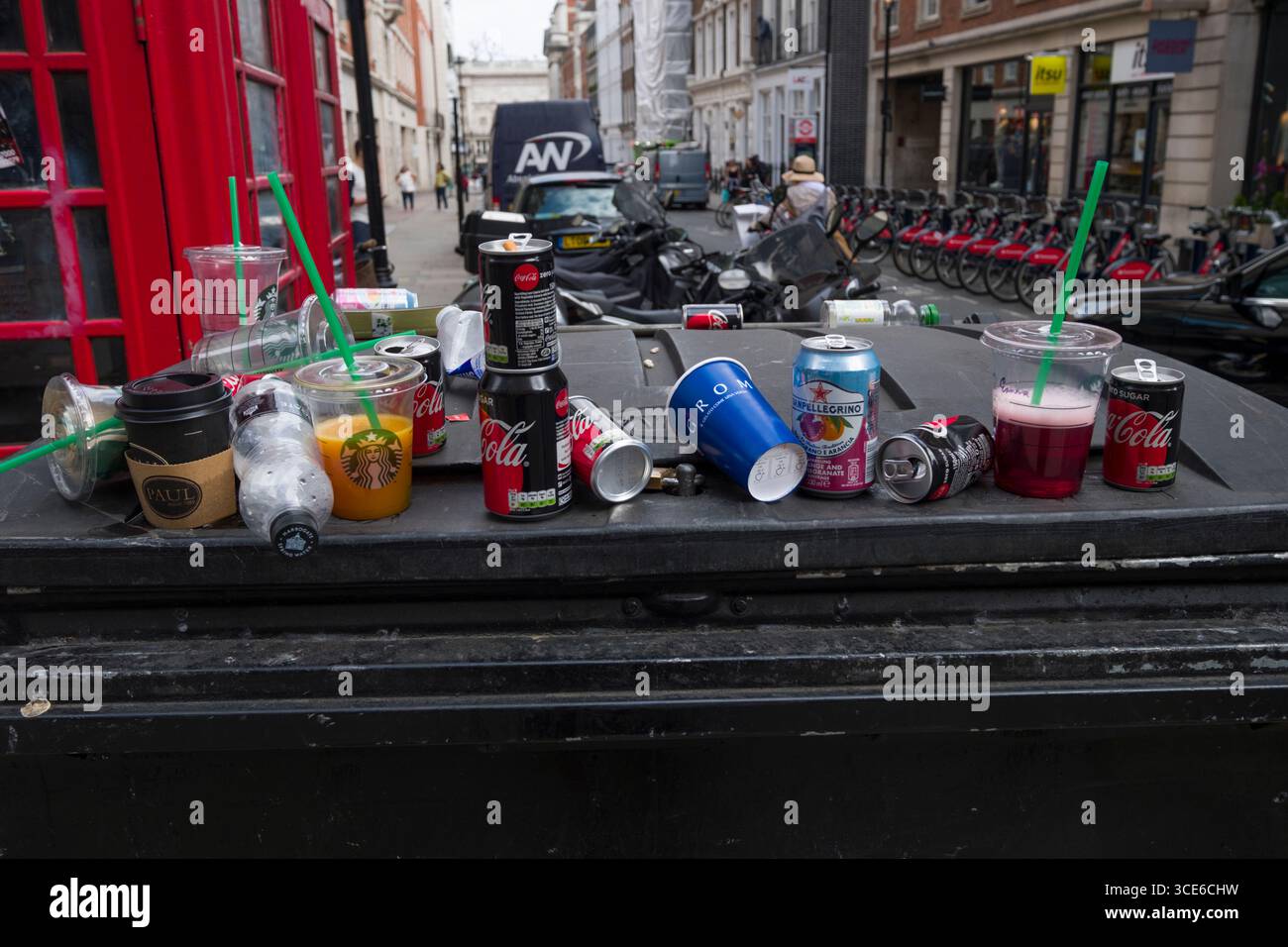 Discarded cups and aluminum cans on top of plastic trash bin, City of ...