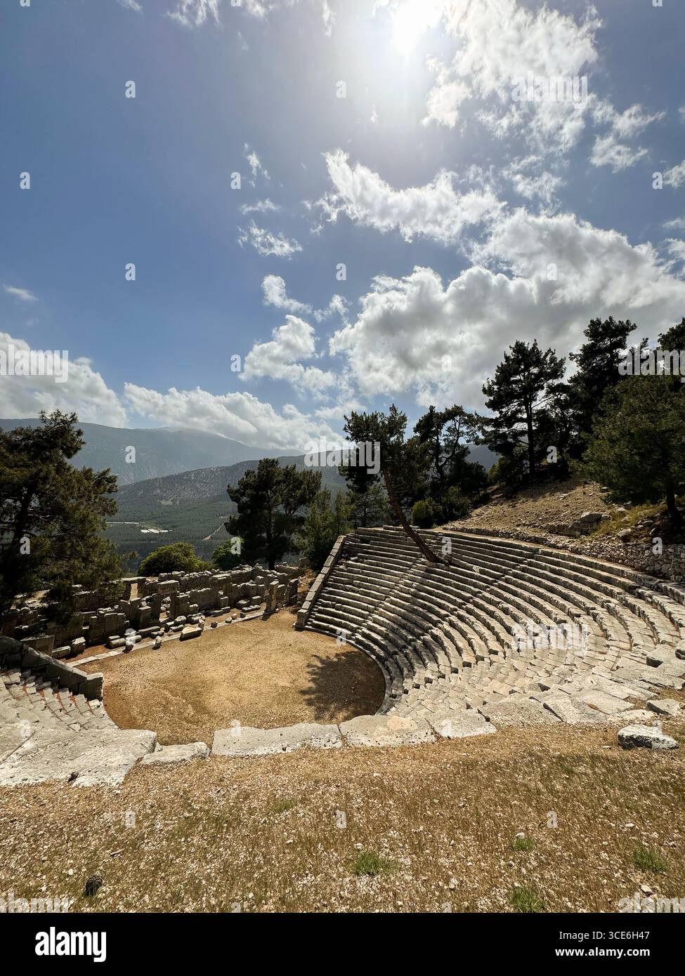Visitors explore an ancient theater surrounded by trees and hills ...