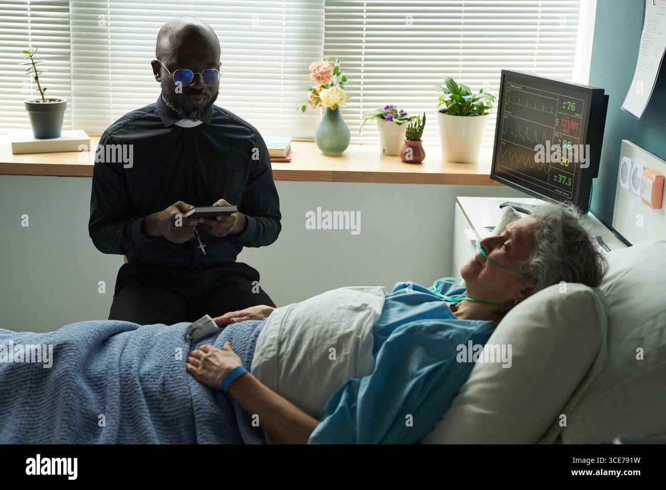 Black Chaplain Praying Beside Senior Caucasian Woman in Hospital Bed ...