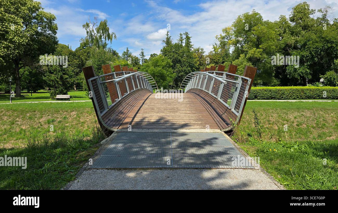 Modern wood and steel footbridge with gently sloping ramp connects park ...