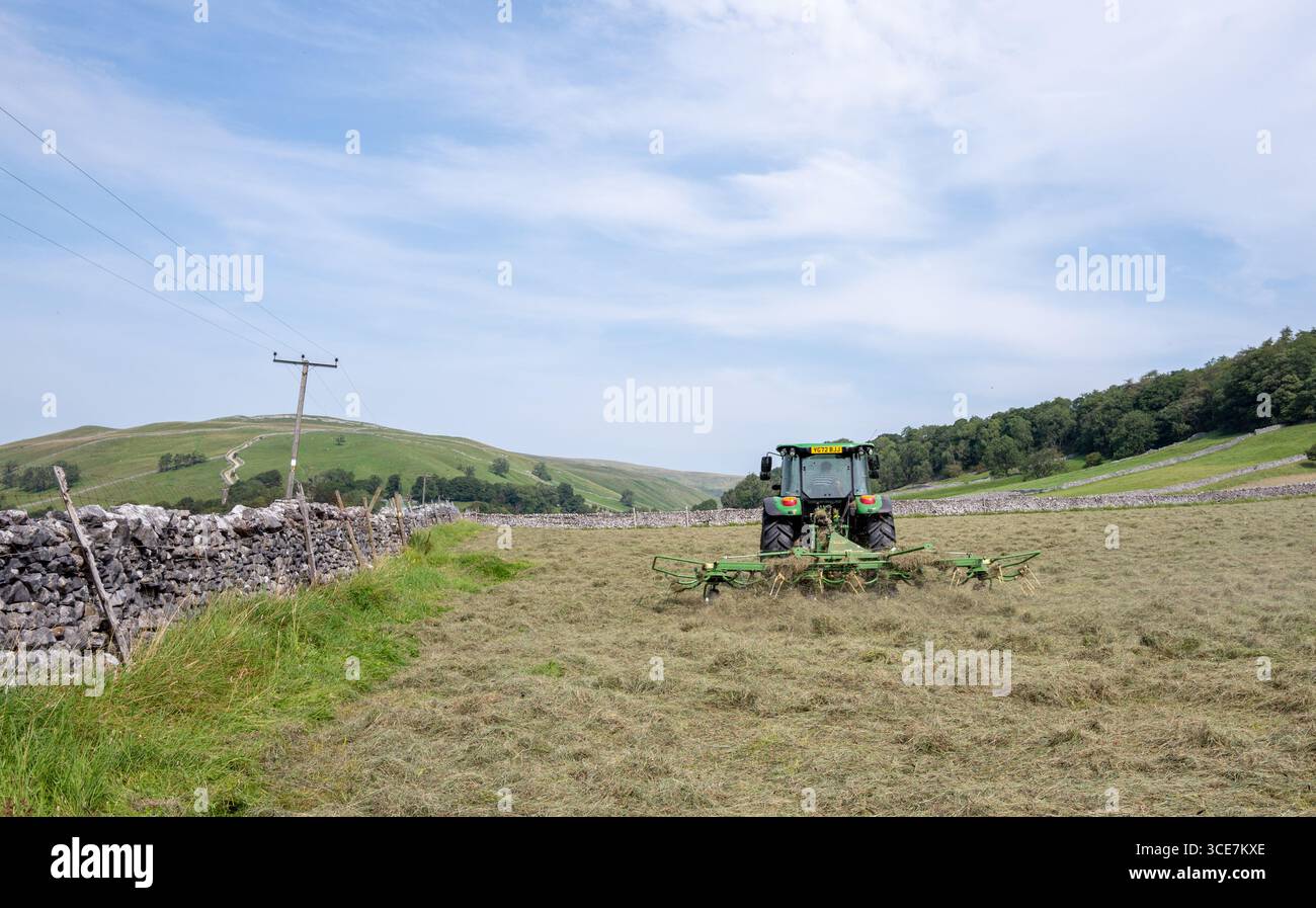 John Deere tractor turning and drying hay during the hay making season ...